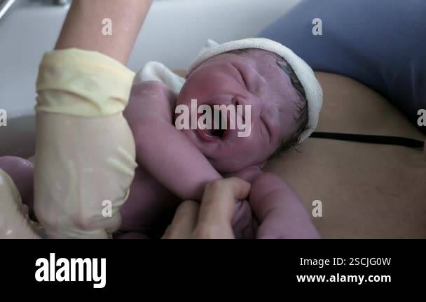 Close-up newborn baby crying for the first time right after birth ...