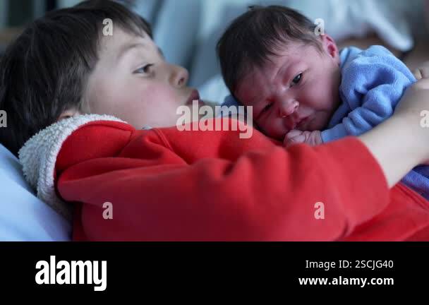 Older brother holding newborn baby close, both wearing cozy outfits ...