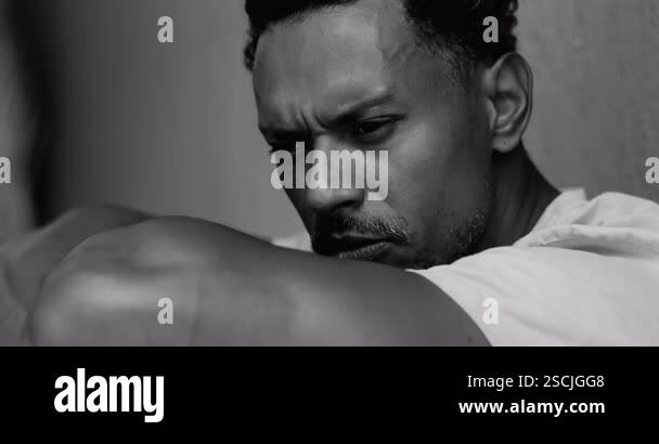 Man of African descent leaning against wall, eyes focused, deep ...