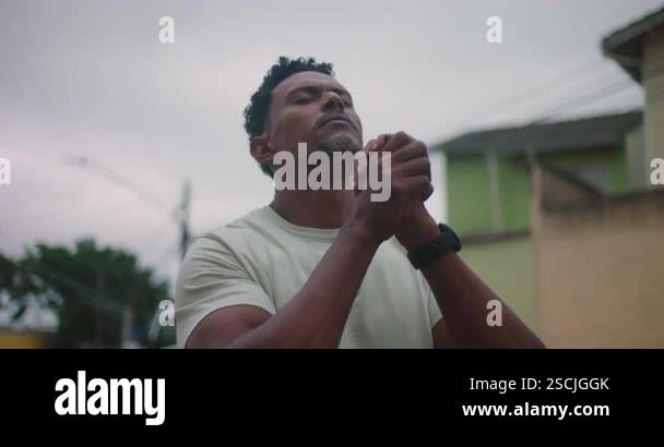 Man of African descent praying intensely, hands clasped, head tilted ...