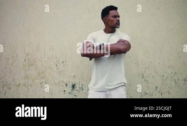 Man of African descent standing against textured wall with arms crossed ...