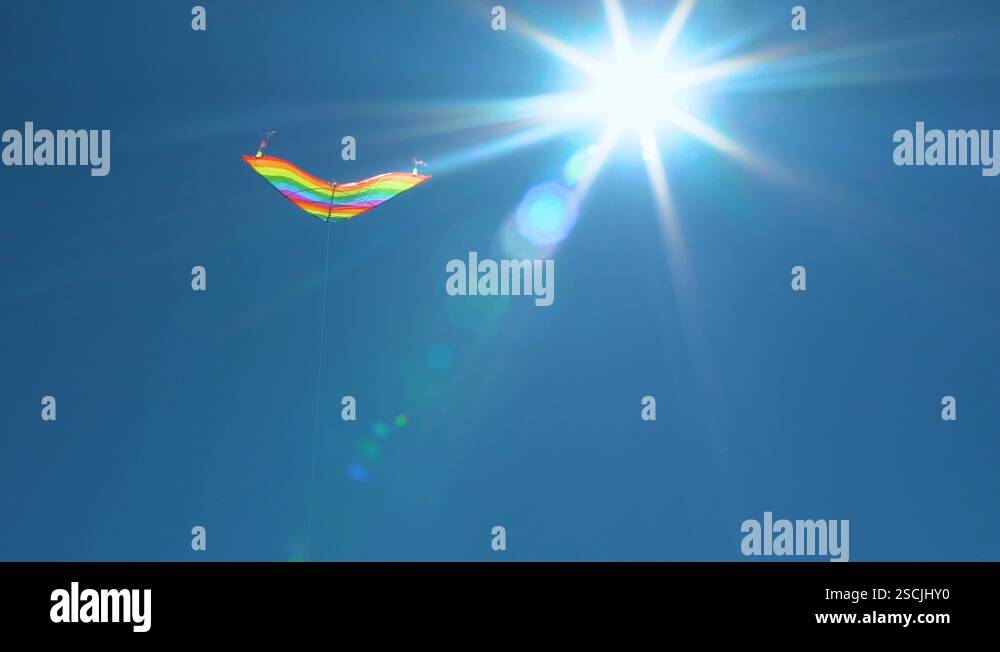 A colored kite in the blue sky. Slowed-down shooting of a kite ...