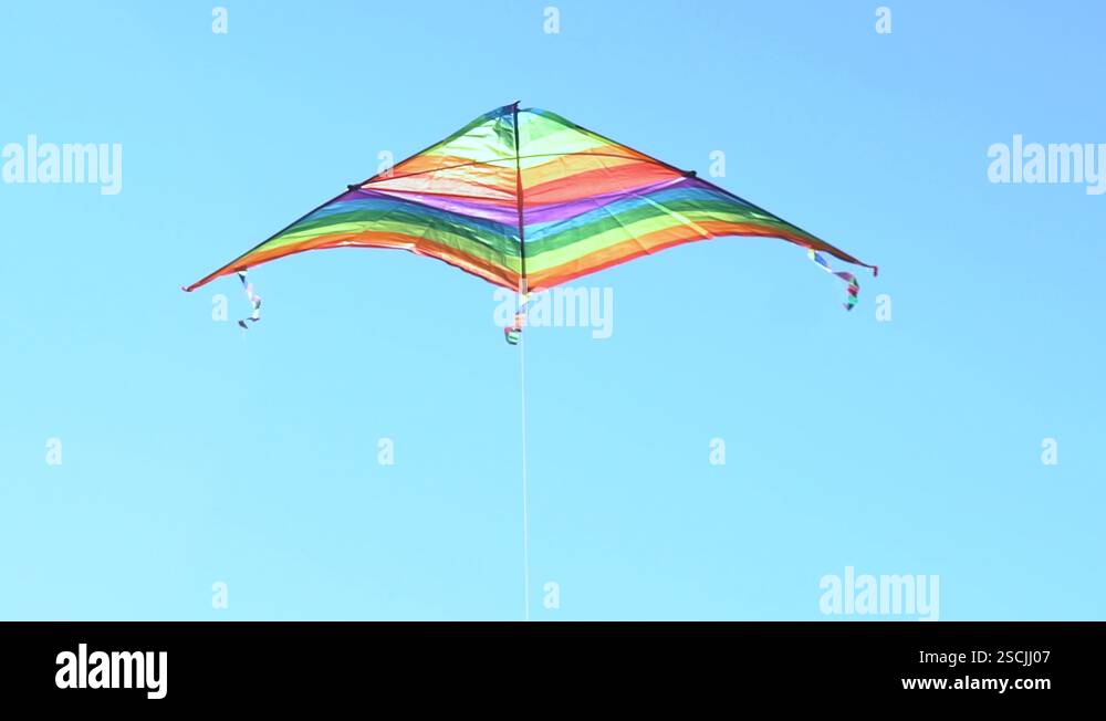 A colored kite in the blue sky. Slowed-down shooting of a kite ...