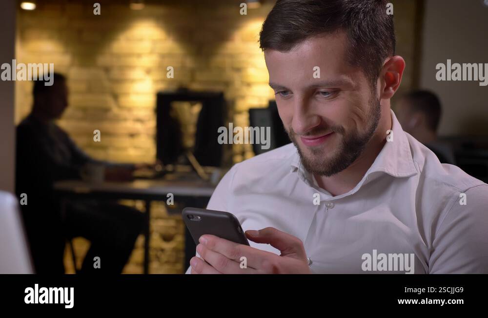 Closeup of young cheerful caucasian businessman browsing on the phone ...