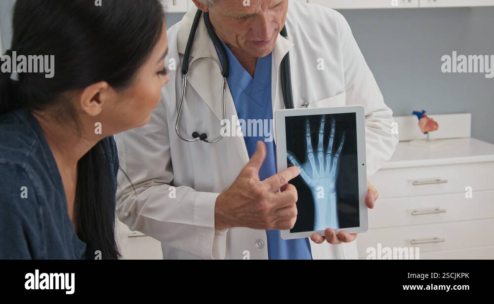Doctor using tablet computer with x-ray of hand explaining injury to ...