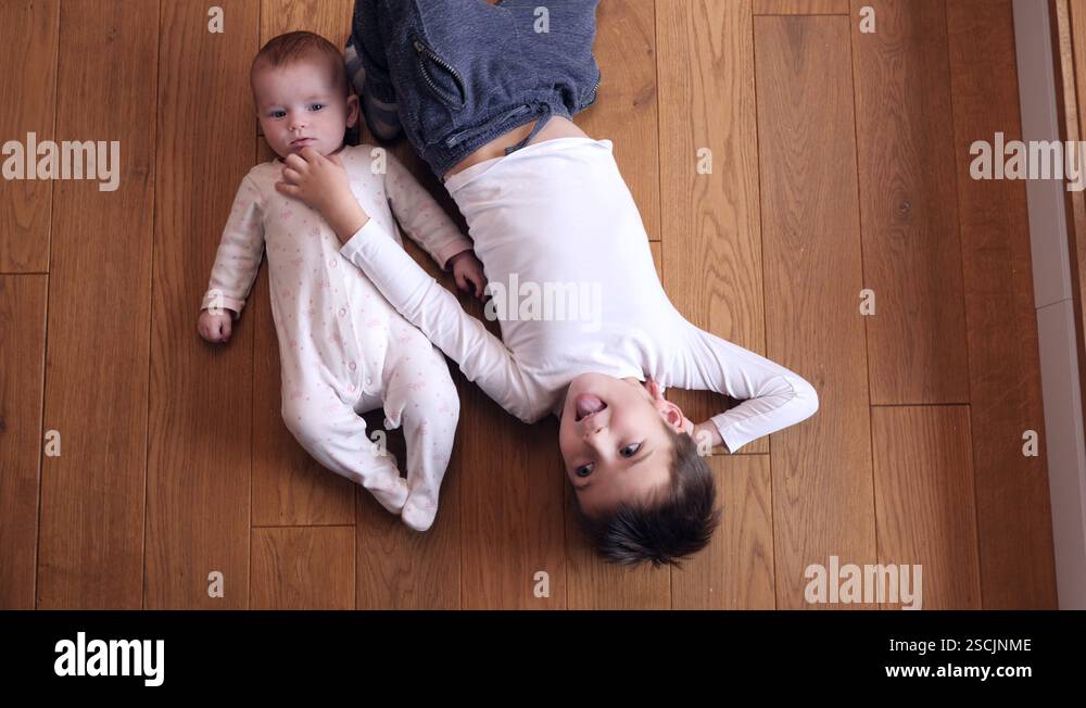 40 Top view kid brother play strokes his baby sister lying on the floor at ho Stock Video ...