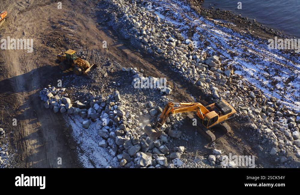 Aerial view of two excavators digging big rocks at sea shore. Ground ...