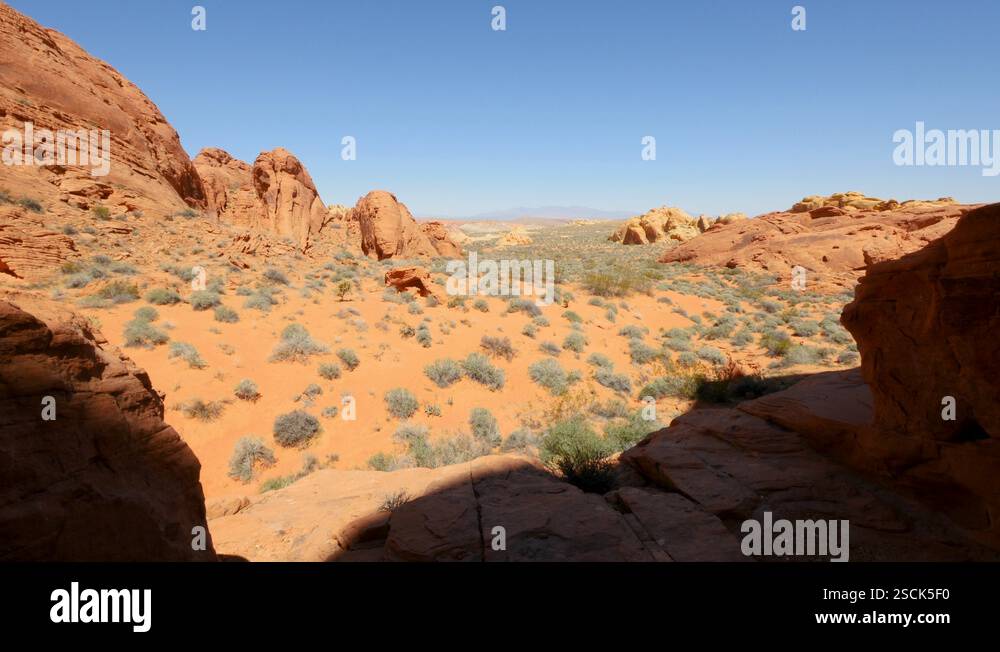 Pan to reveal mother and son on windy rock cliff above sandy desert ...