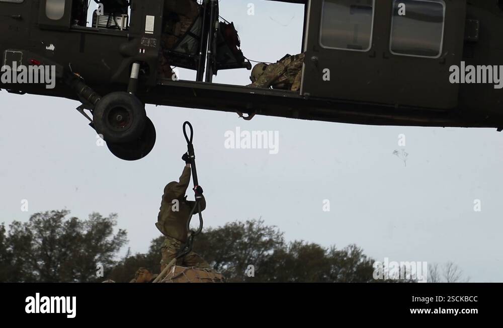 Soldier positioning sling load to attach to approaching UH-60 Black ...