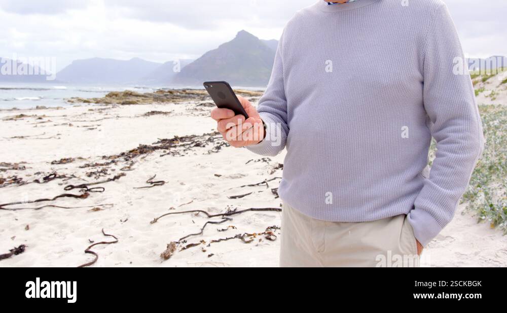 Mid section of old caucasian senior man using mobile phone at beach 4k ...