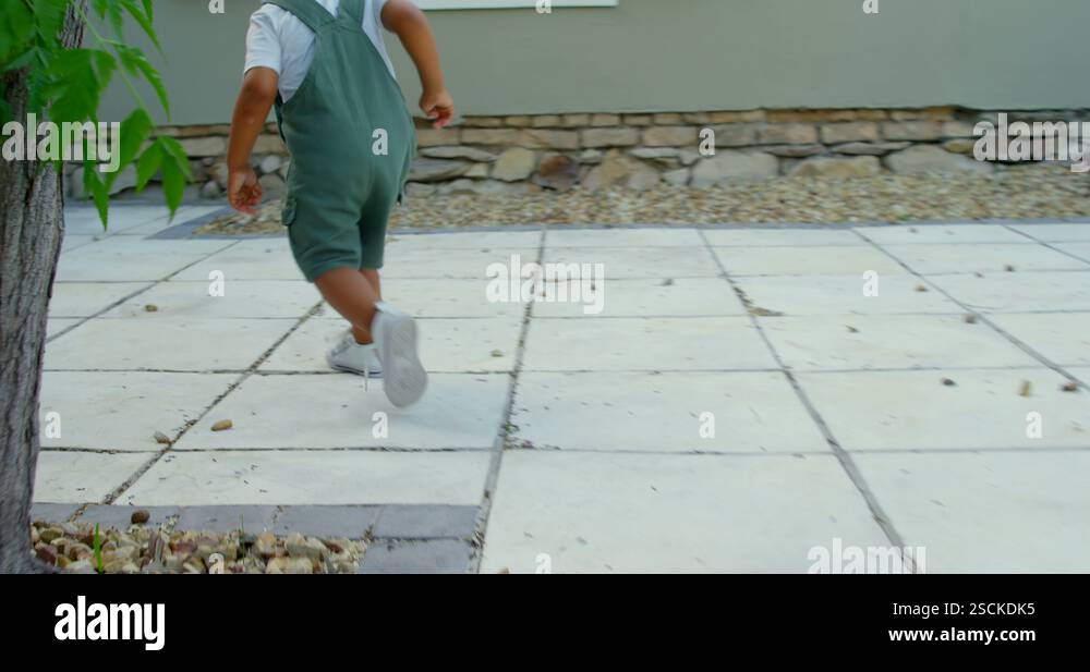 Rear view of cute little black baby playing in back yard of their home ...