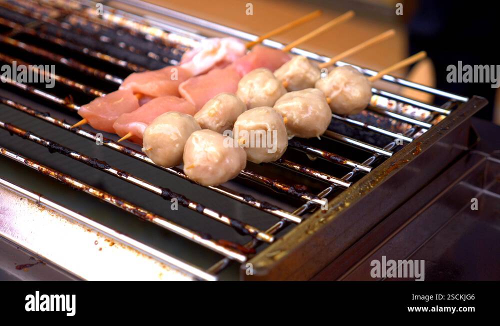 Traditional street food of Thailand. Cooking small kebabs on the grill ...
