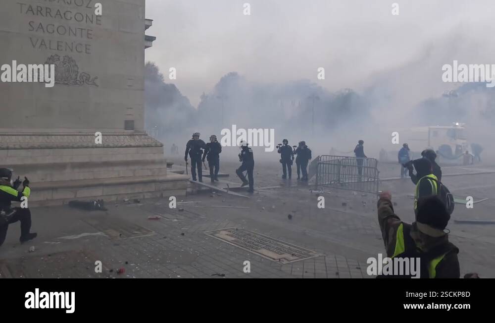 Man picking up large rock before throwing it toward riot police office ...