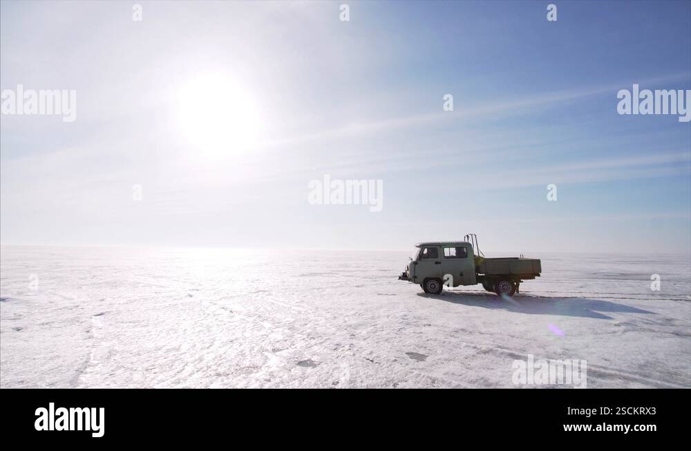 Russian car UAZ 3303 drives on ice andn snow of frozen lake. Beautiful ...