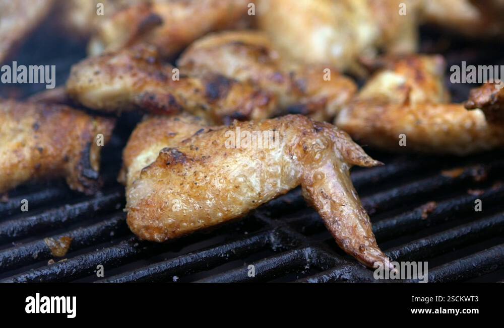 Slow Motion man using tongs to turning spicy chicken wings on grill ...