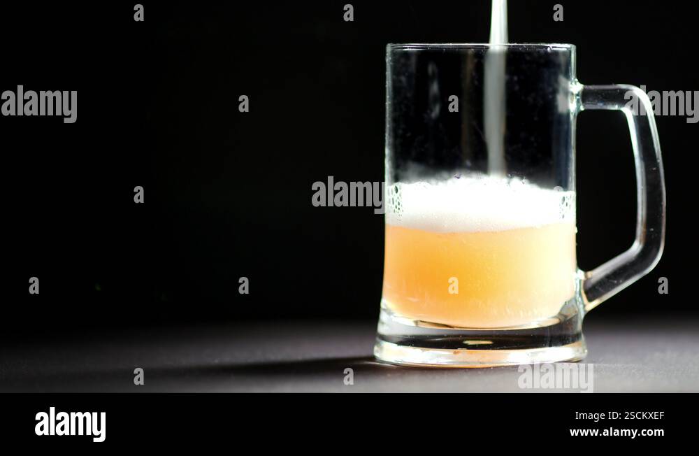 Process of filling huge glass mug with frothy alcohol malt beverage ...
