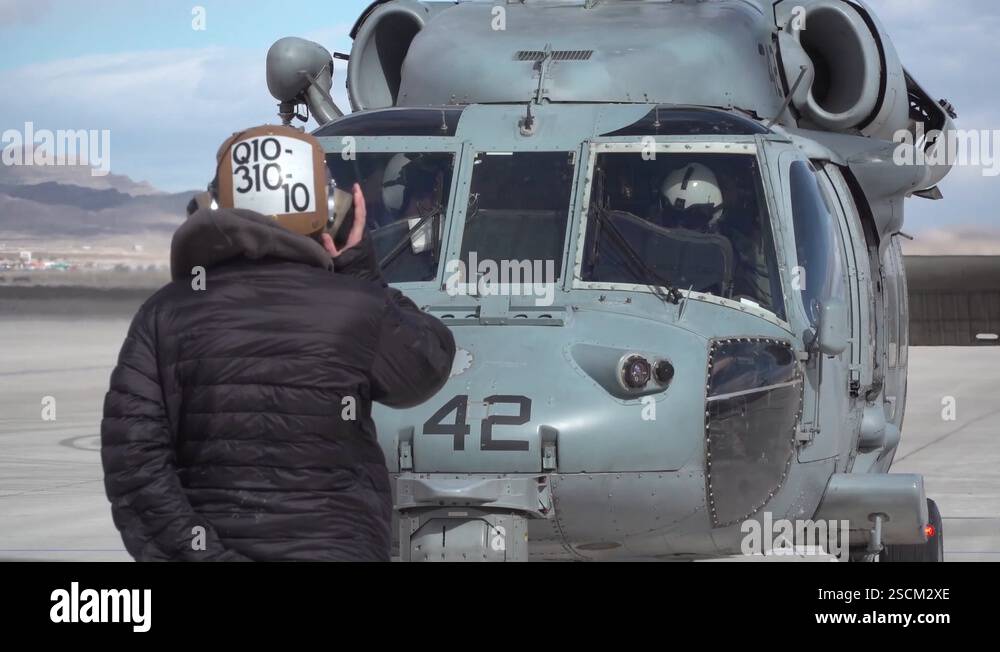 Ground crew adjusting headset while waiting for MH-60 Seahawk to take ...