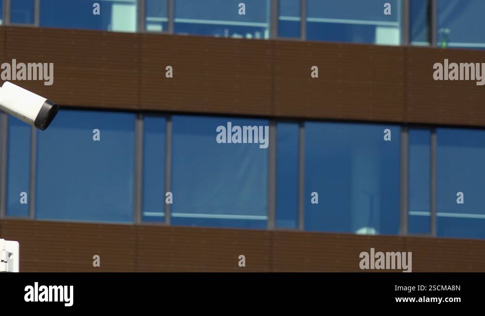 Cameras on a pole in an urban area - an office building in the blurry ...