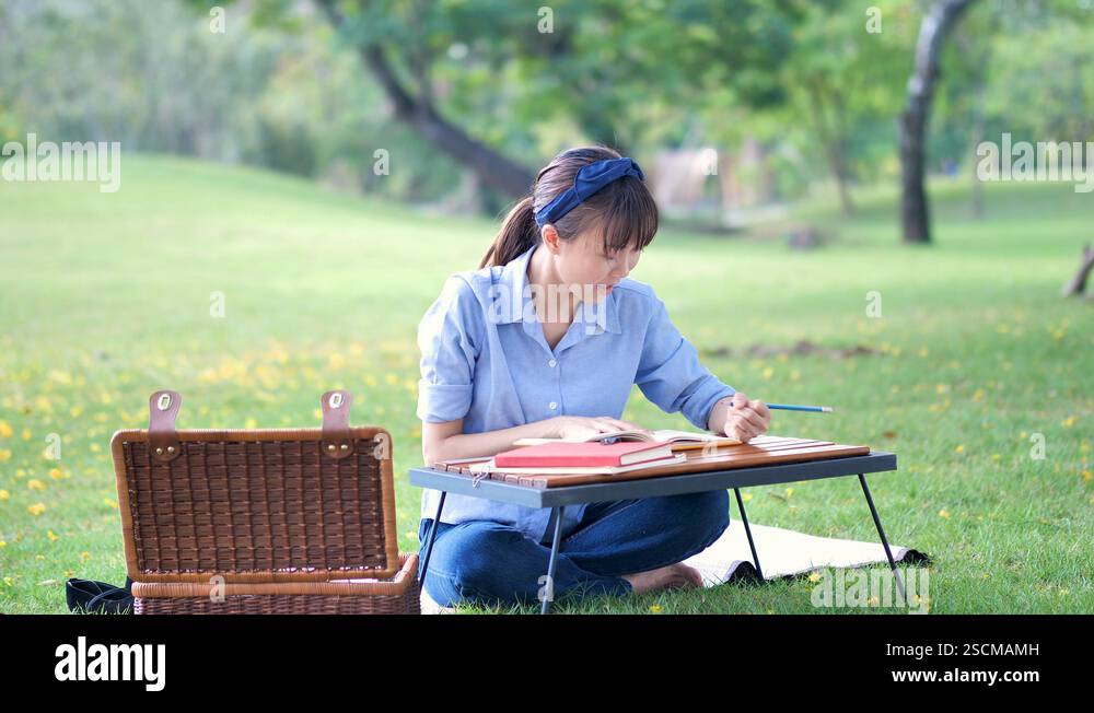 Young beautiful Asian woman are write on notebook and pose getting an ...