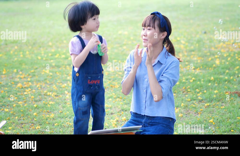 Asian family with Mother and daughter playing blow soap bubbles having ...