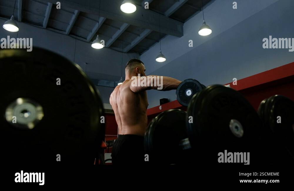 Bodybuilder lifts heavy weights in the gym, exercise the neck and ...