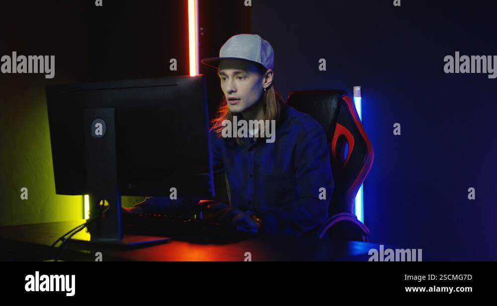 Professional young guy gamer sitting in the dark space of the Internet ...