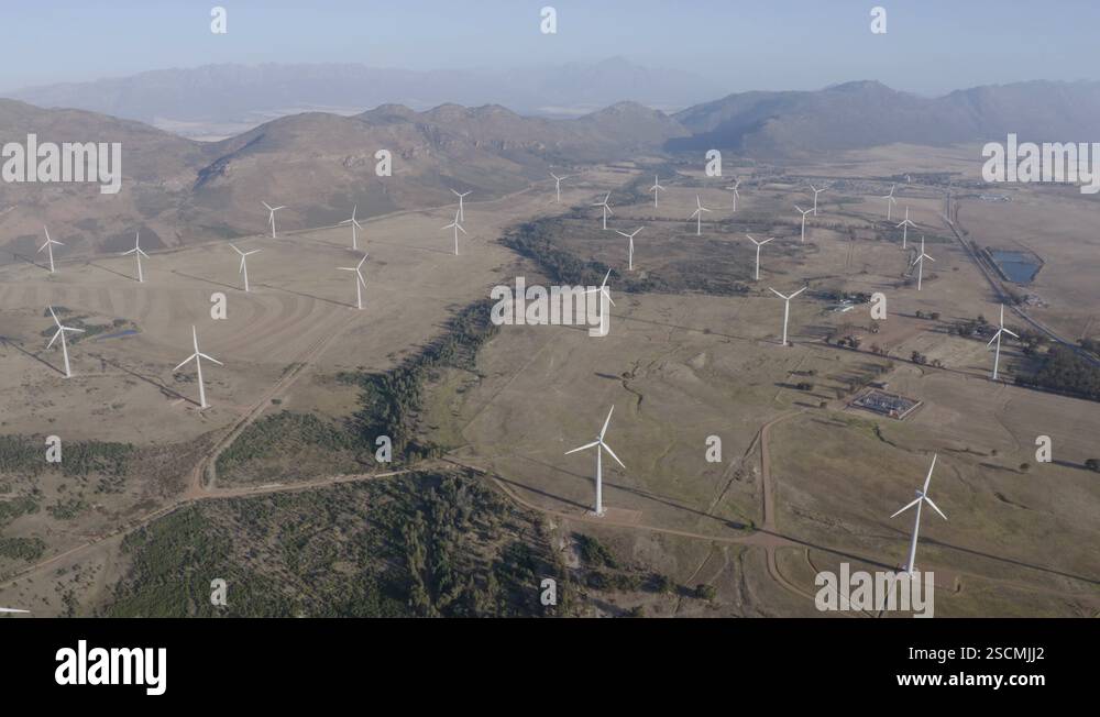 4K wide angle high scenic aerial view of wind turbines turning on a ...