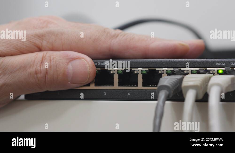 Male Hand Inserts The Orange Data Cable Into The Gigabit Network Switch ...