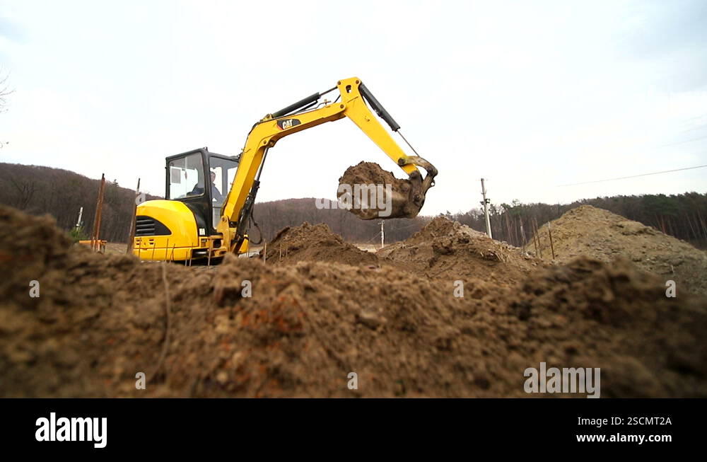 Slow motion of a digger digging a pit and throwing dirt. Close-up of a ...