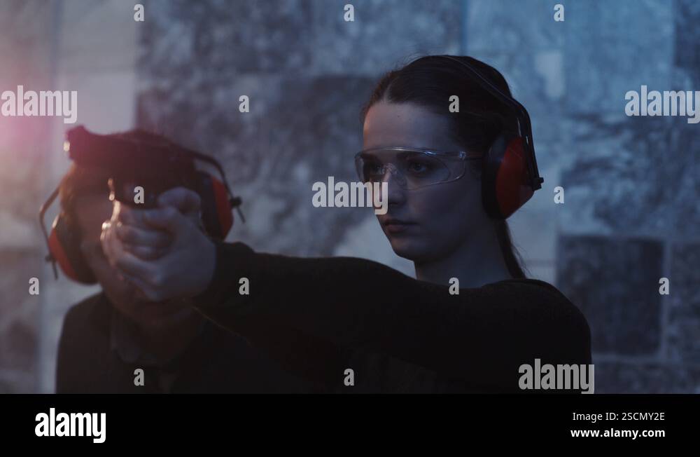 A man teaches a woman how to shoot a gun indoors pistol speed firing ...