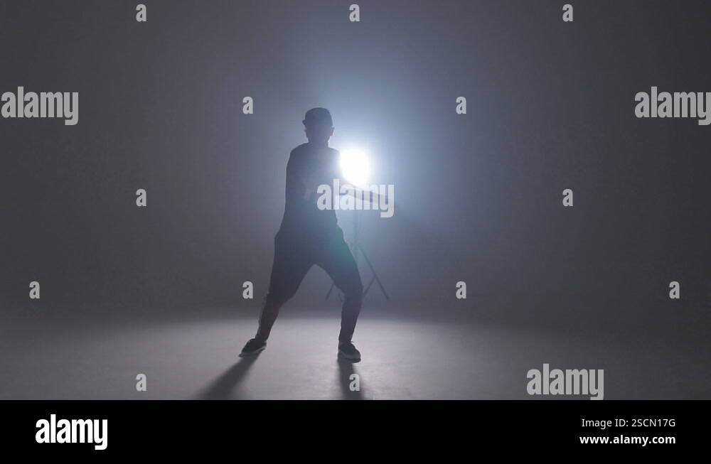 Young man dancer dancing funky hip hop on isolated studio neon blue ...