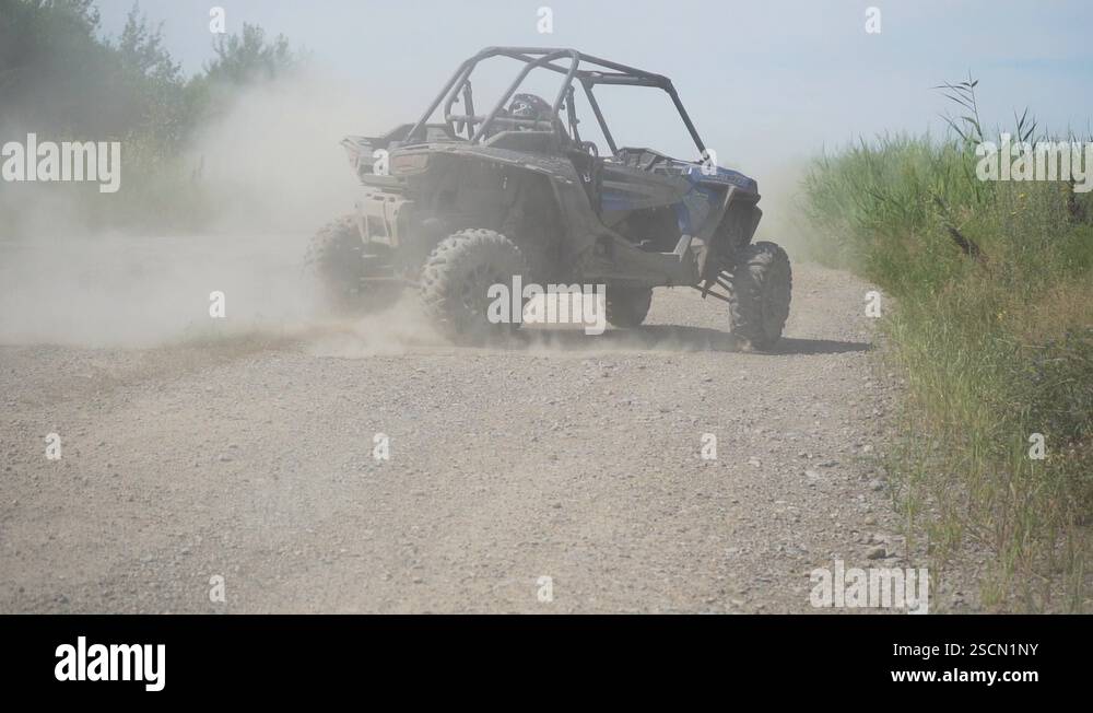 Biker on ATV enters the turn at high speed, kicking up dirt and dust ...