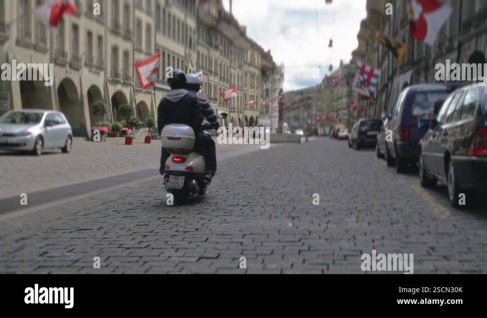 Two people riding a moped on the streets of the ancient city in Europe ...