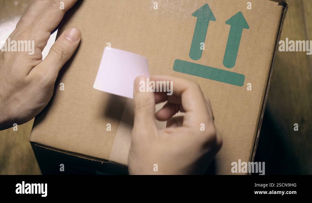 Man sticks a white sticker label to parcel carton box. Place for ...