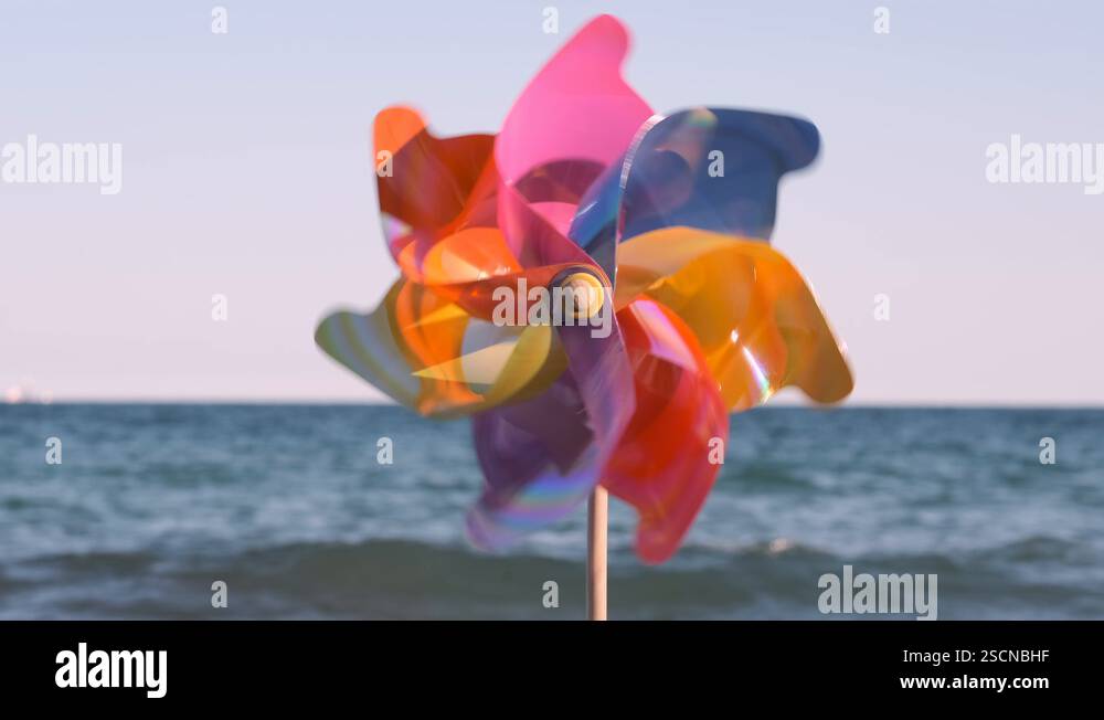 A rotating multi-colored plastic pinwheel with a blowing wind stands ...