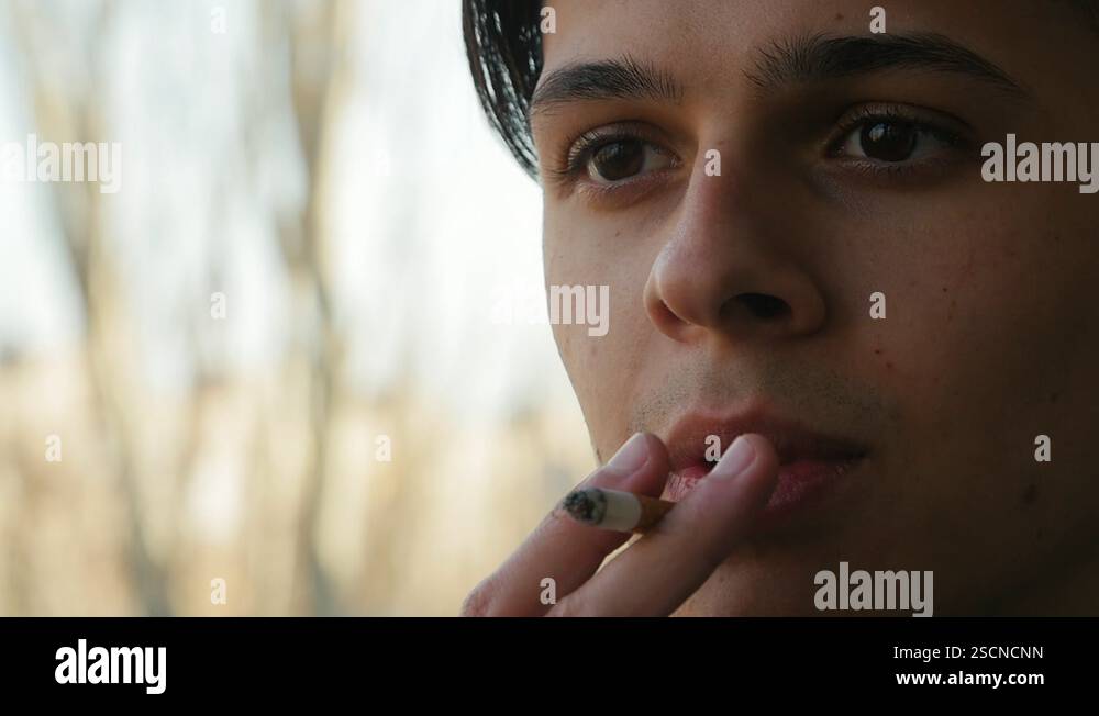 handsome boy smoking cigarette outdoors. Face of smoking person in slow ...