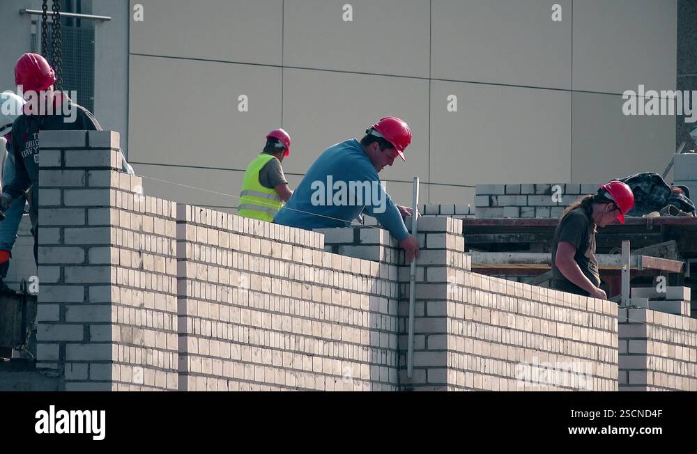 Builder worker team laying bricks wall and man take a brake with ...