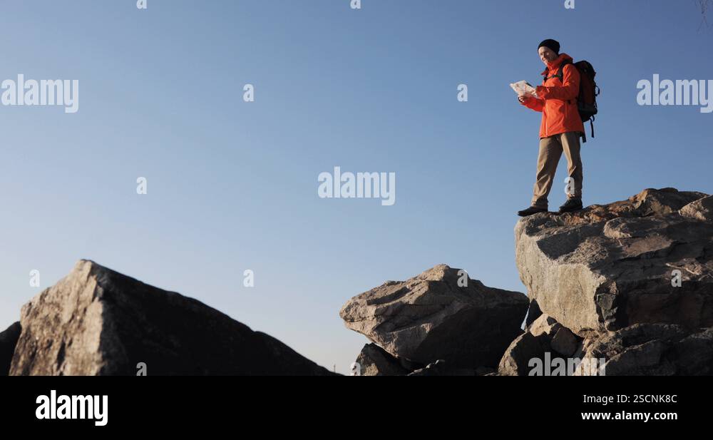 Man hiker is looking at the map in mountains checking the route ...