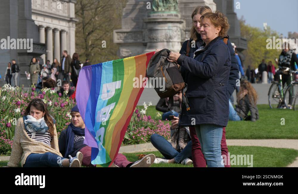 Two women are keeping a rainbow flag with PACE word on a lawn in spring ...