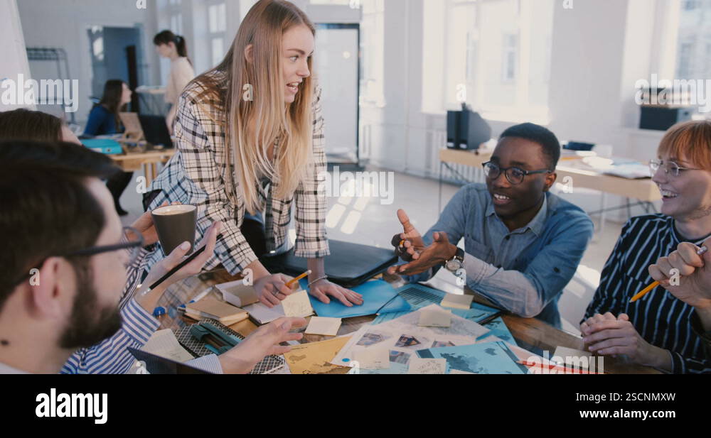 Young positive multiethnic company employees smile, work together ...