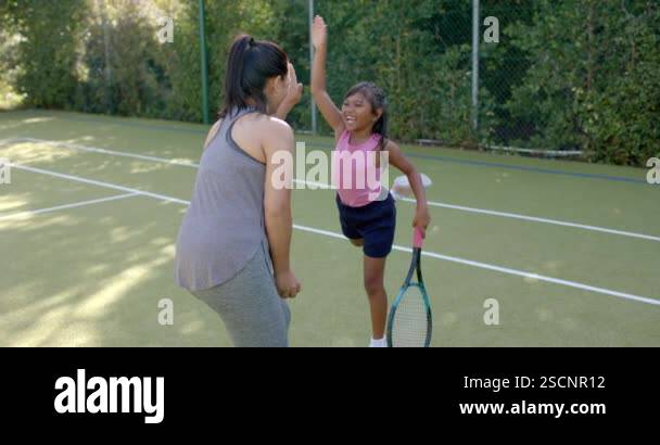 Playing tennis, woman coaching young girl on court, enjoying outdoor ...