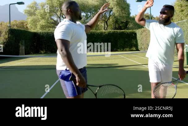 High-fiving, two friends celebrating on tennis court after successful ...