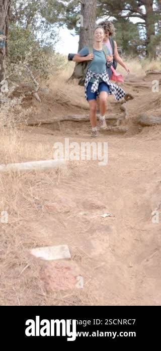 Vertical video: Hiking on trail, two women with backpacks enjoying ...