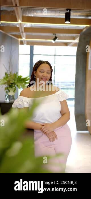 Vertical video: Leaning on counter in modern office, smiling woman ...