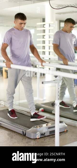 Vertical video: Man in rehabilitation walking on treadmill using ...