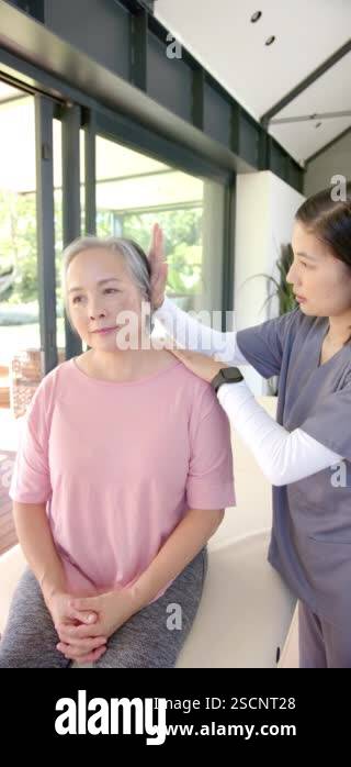 Vertical video: Physiotherapist treating senior woman with neck pain at ...