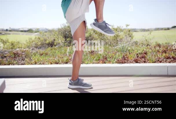 Exercising outdoors, man stretching leg on wooden deck in athletic wear ...