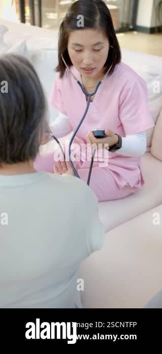 Vertical video: Nurse in pink scrubs checking senior patient's blood ...