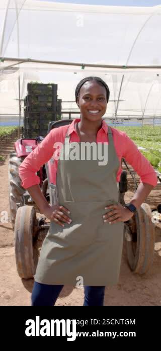 Vertical video: Smiling woman in apron standing in hydroponic farm ...