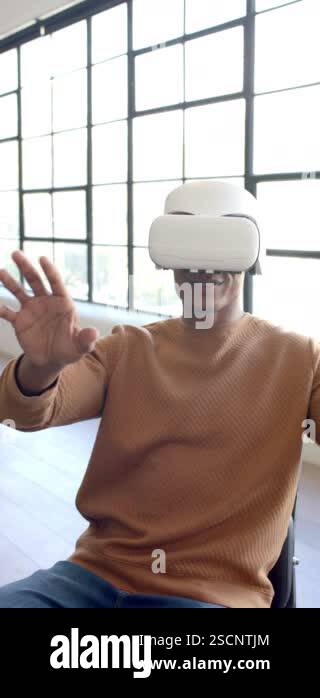 Vertical video: Using VR headset, man sitting and experiencing virtual ...